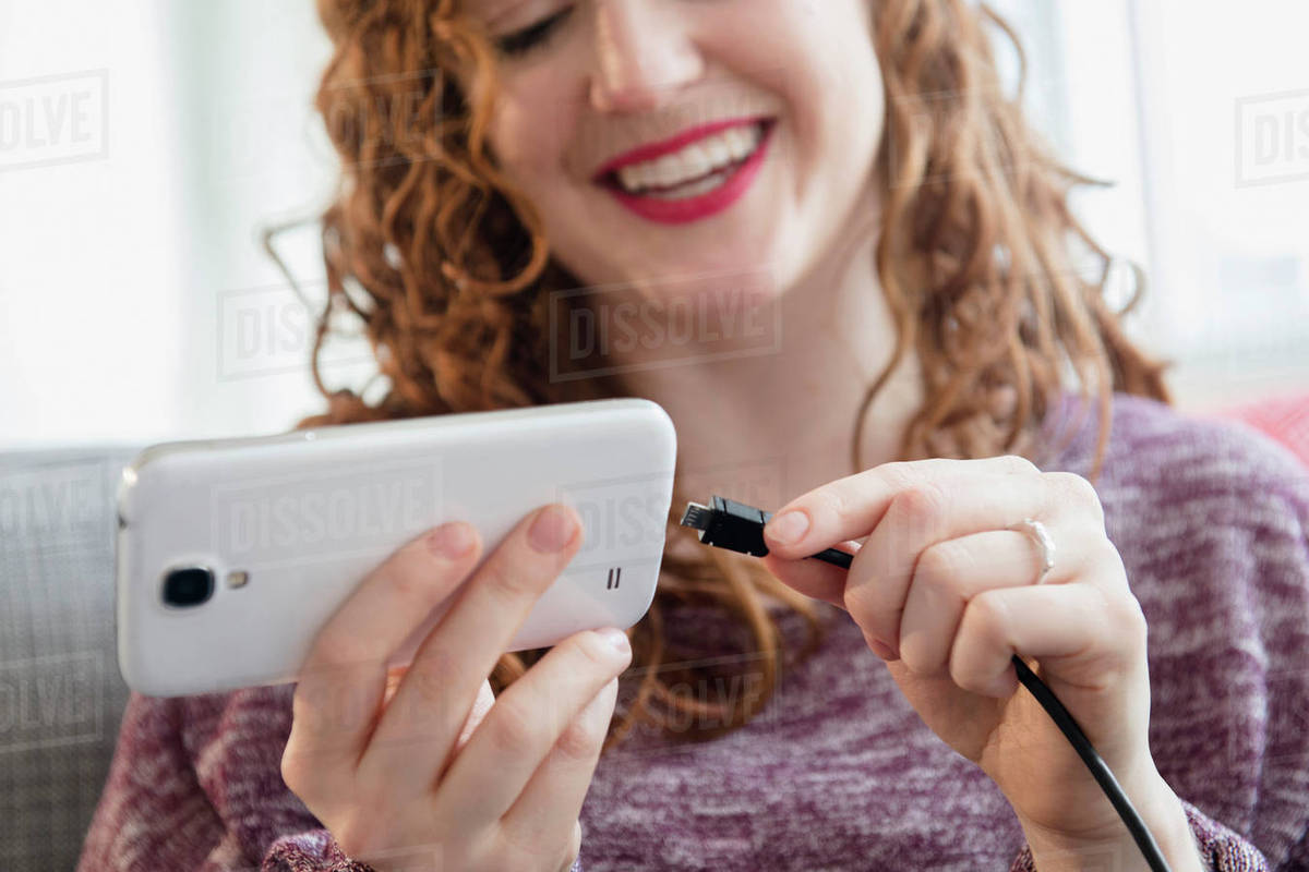 Caucasian woman connecting cord to cell phone - Royalty-free Stock ...