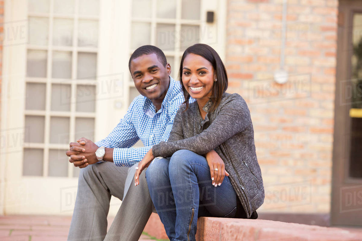 Smiling couple sitting on steps - Stock Photo - Dissolve