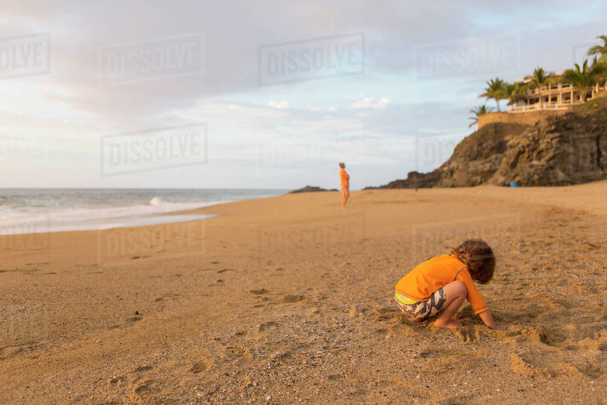 Caucasian boy digging in sand on beach - Stock Photo - Dissolve
