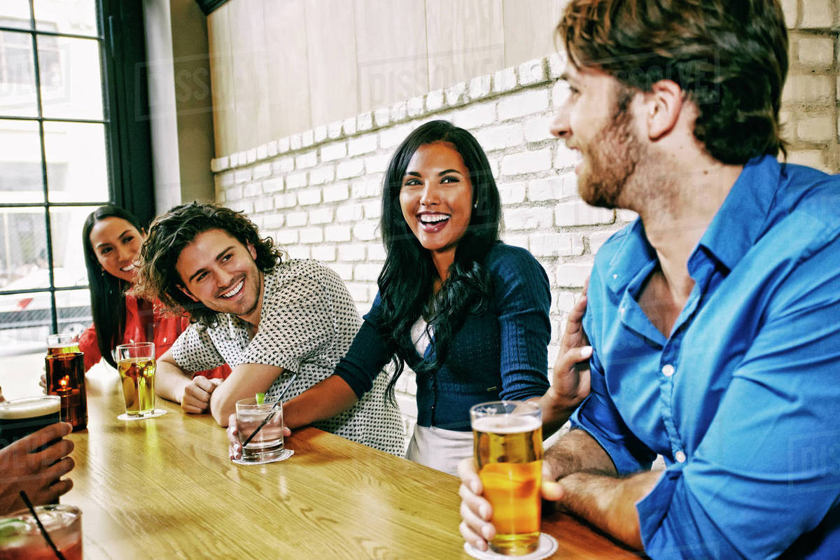 Smiling friends drinking at table in bar - Royalty-free Stock Photo ...