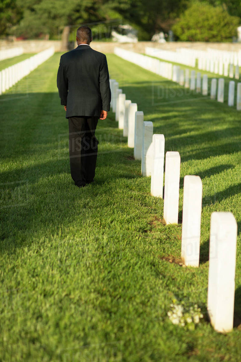Black man leaving bouquet at gravestone at military cemetery - Stock ...