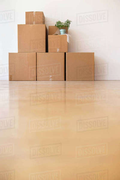 Cardboard boxes stacked against wall in empty apartment - Royalty-free ...
