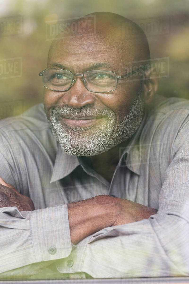 Smiling Black man behind window - Stock Photo - Dissolve