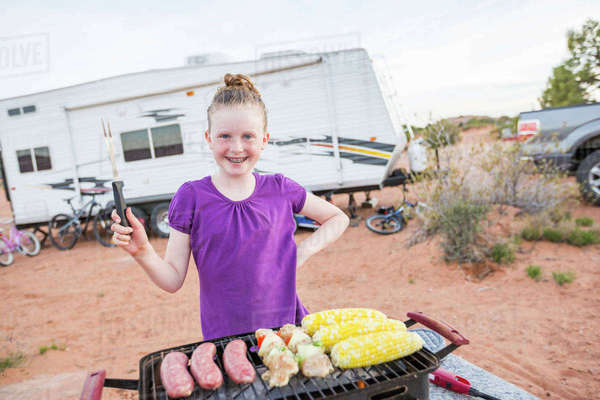 Caucasian girl cooking on grille while camping - Stock Photo - Dissolve