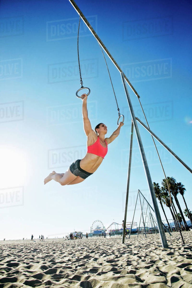 Caucasian woman using gymnastic rings at beach - Royalty-free Stock ...