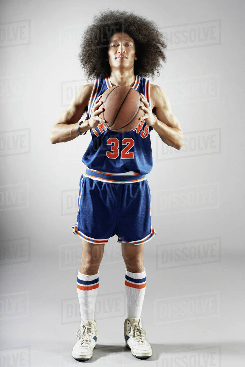 Mixed race basketball player holding basketball - Stock Photo - Dissolve