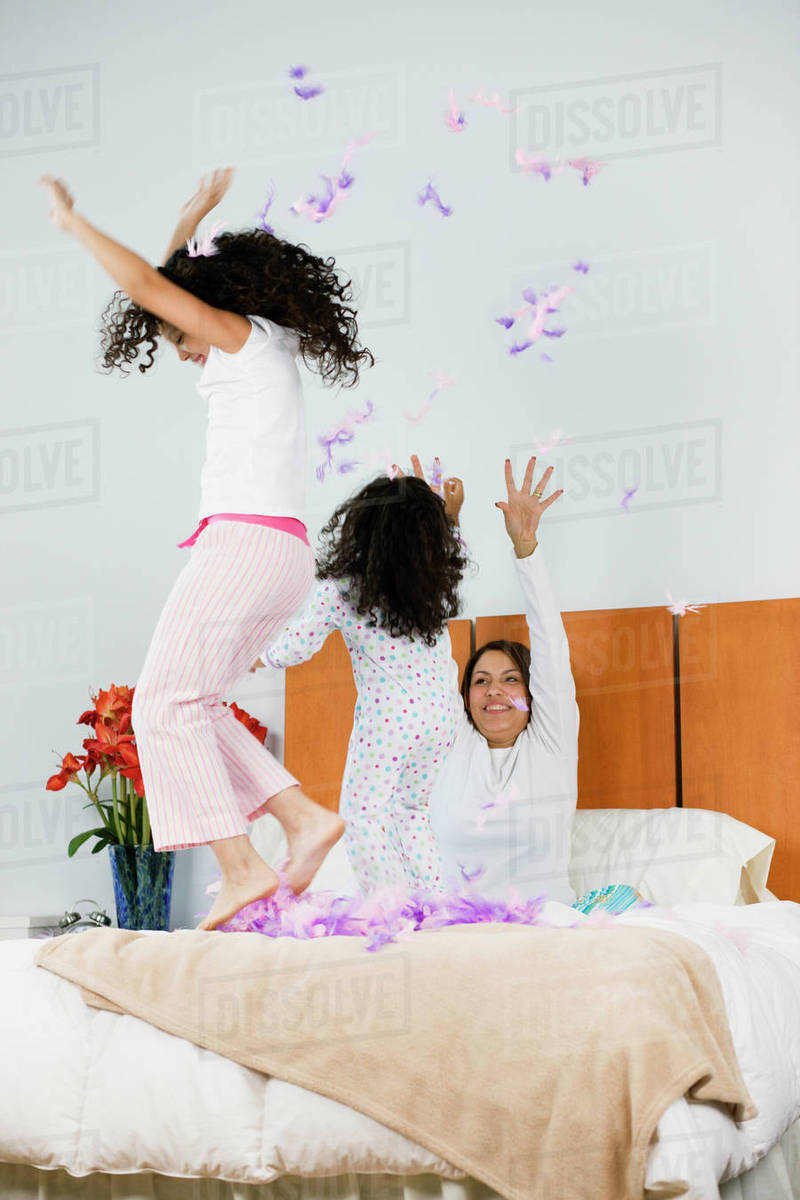 Hispanic mother and daughters throwing feathers in bedroom - Royalty ...