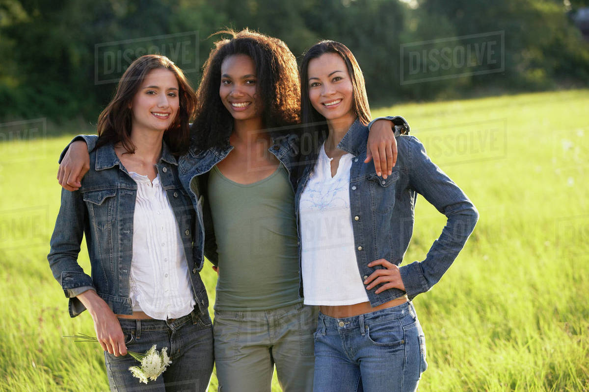Portrait of three women hugging in meadow - Royalty-free Stock Photo ...