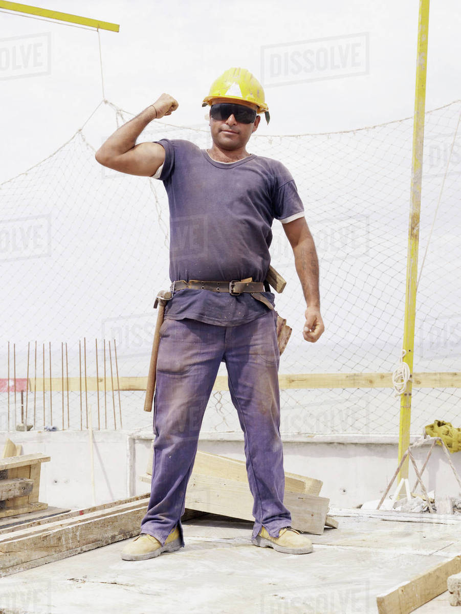 Hispanic worker flexing biceps on construction site - Royalty-free ...