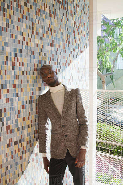 African man in tweed jacket leaning against tiled wall - Stock Photo ...
