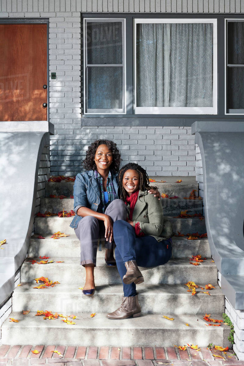Black mother and daughter sitting on front stoop - Royalty-free Stock ...