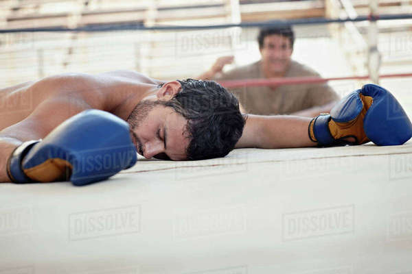 Knocked-out Hispanic boxer laying on ground - Stock Photo - Dissolve