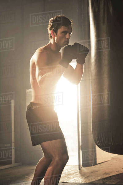 Caucasian boxer hitting punching bag - Stock Photo - Dissolve