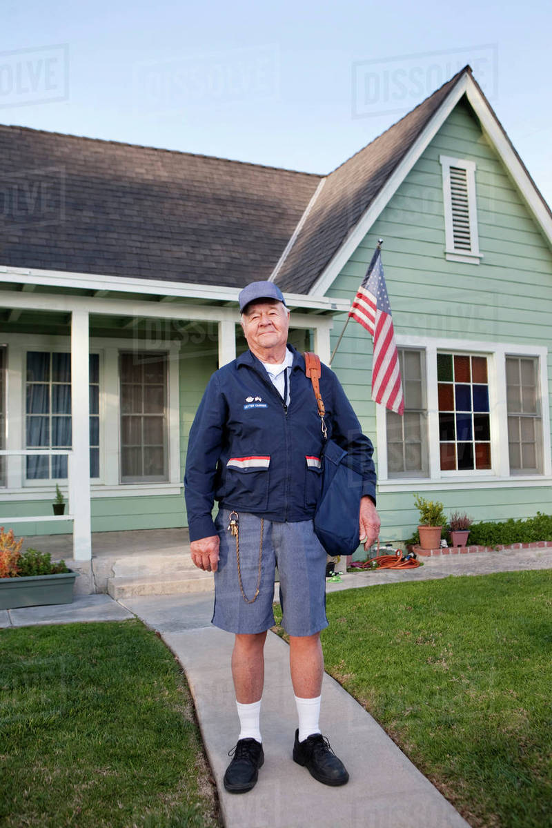 Caucasian mailman standing in front yard - Stock Photo - Dissolve