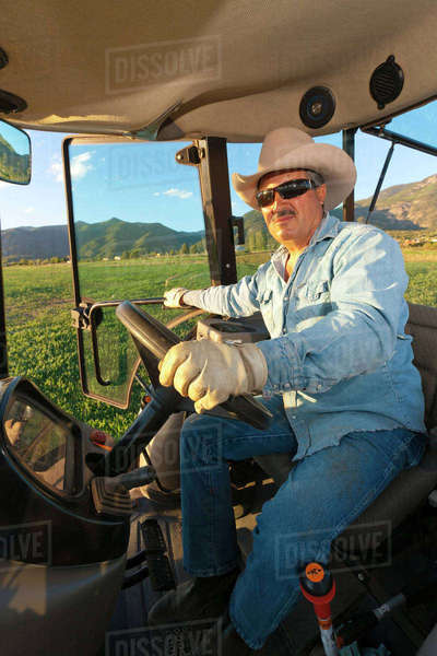 Hispanic man driving tractor - Royalty-free Stock Photo | Dissolve
