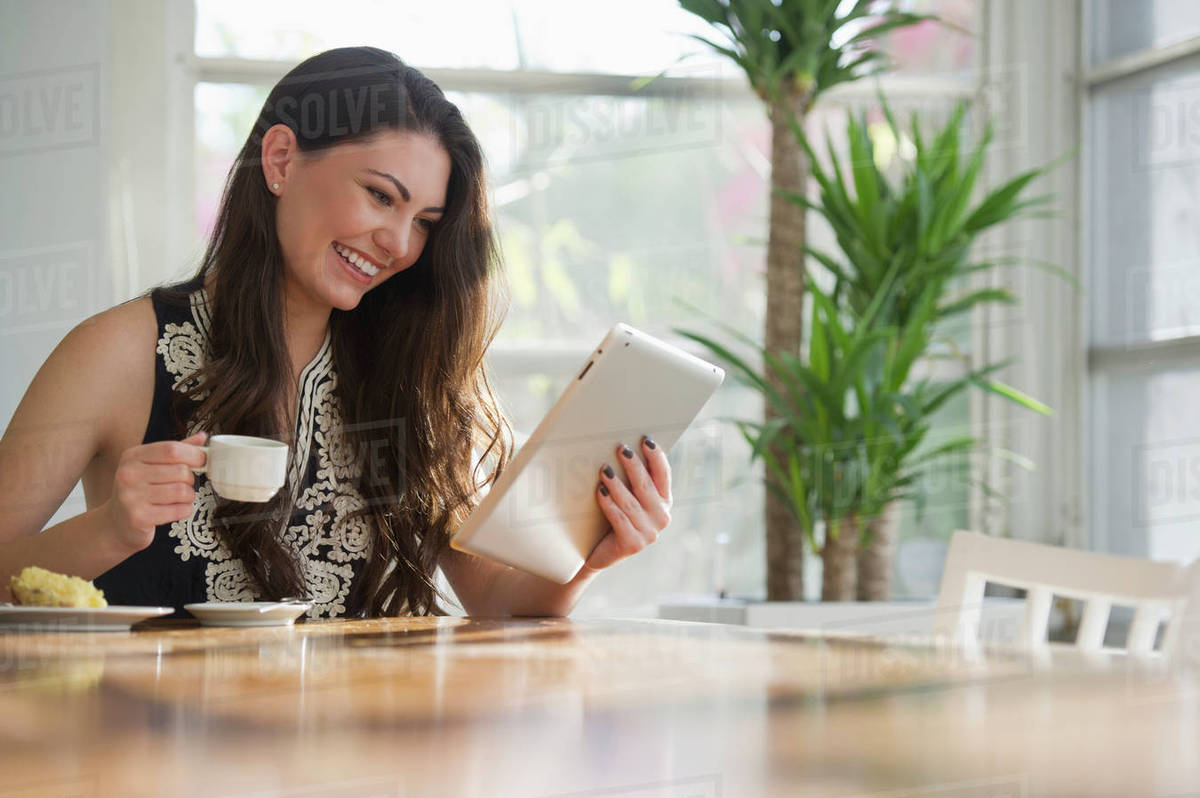 Hispanic woman drinking coffee and using digital tablet - Royalty-free ...