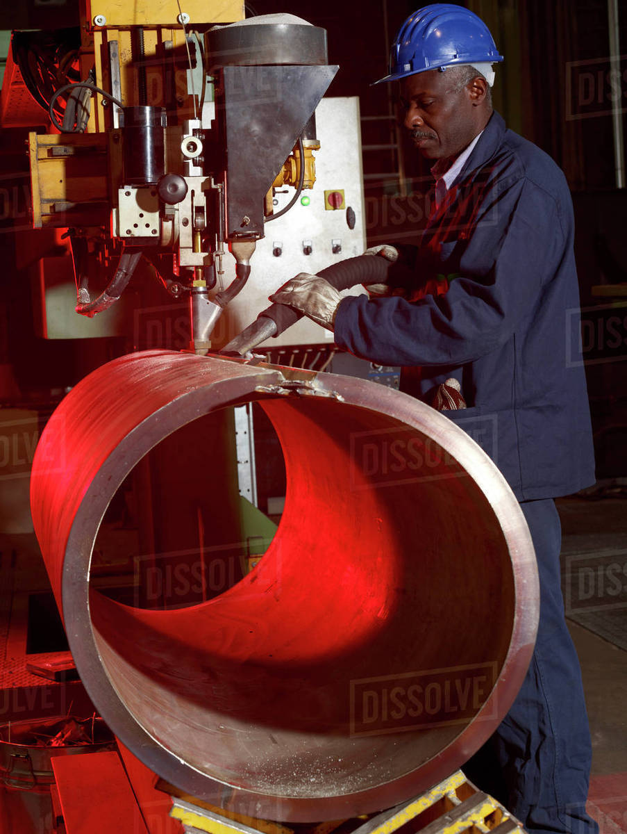 Worker working on steel pipe in factory - Stock Photo - Dissolve
