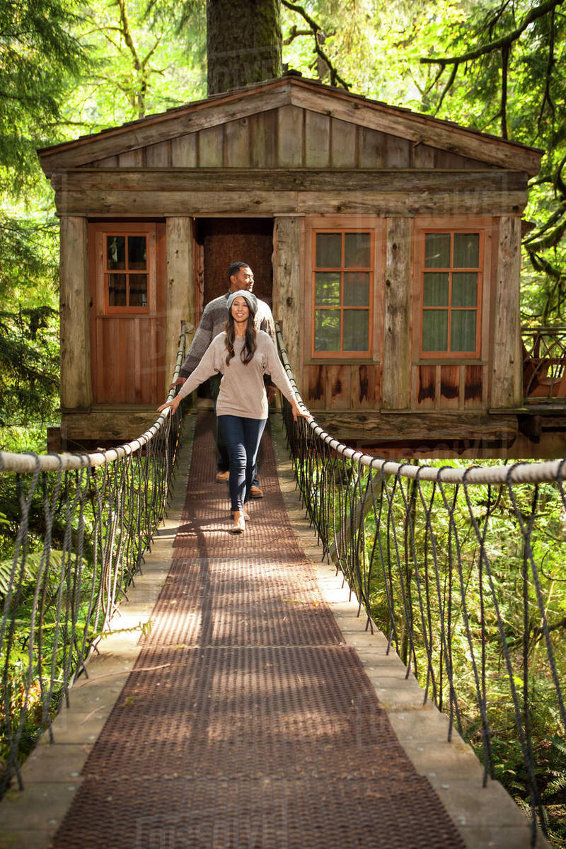 Couple on walkway of remote tree house - Stock Photo - Dissolve