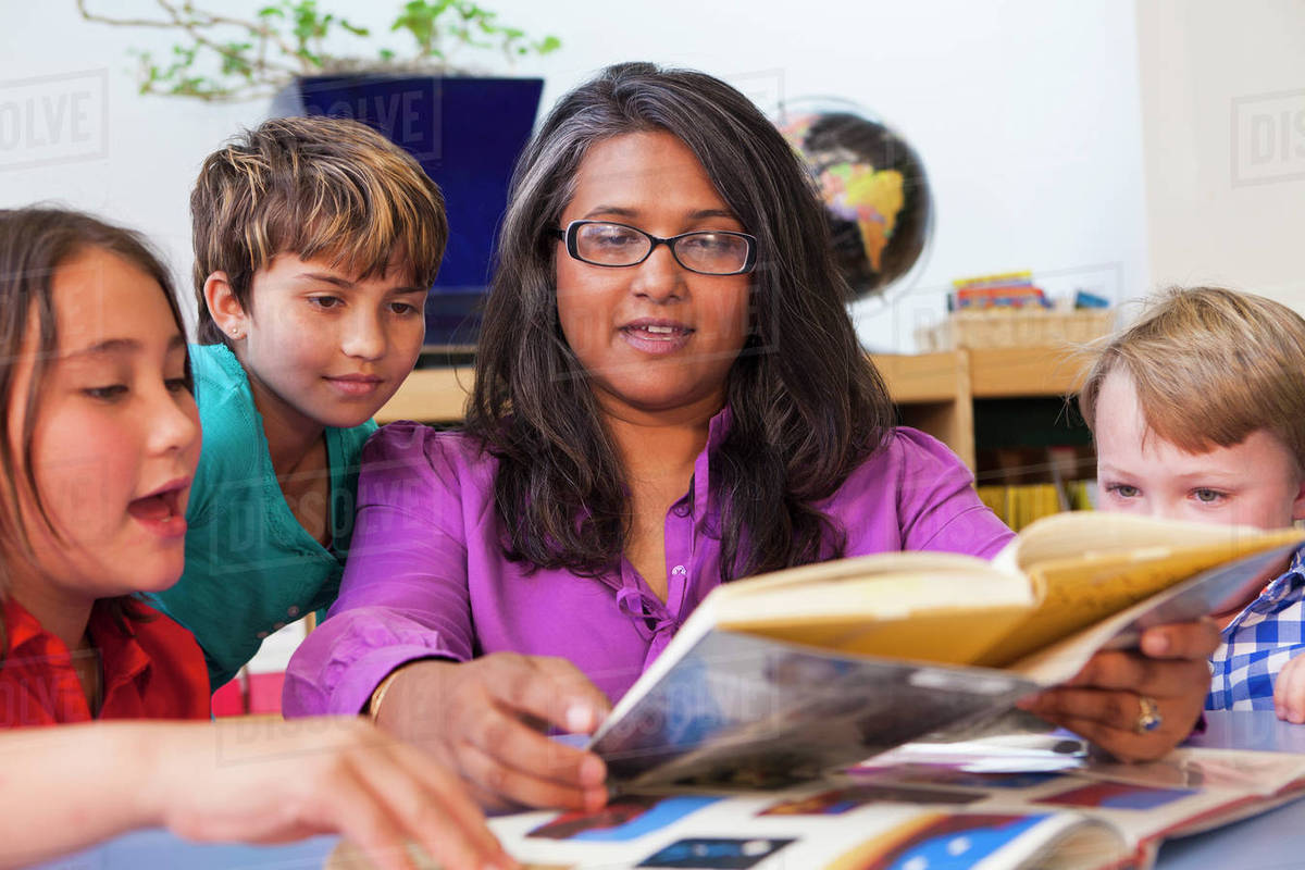 Teacher reading book to students in classroom - Royalty-free Stock ...