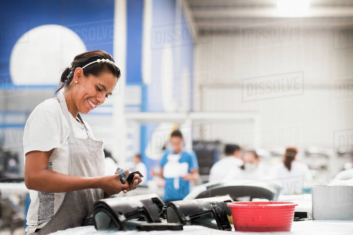 Worker smiling in manufacturing plant - Royalty-free Stock Photo | Dissolve
