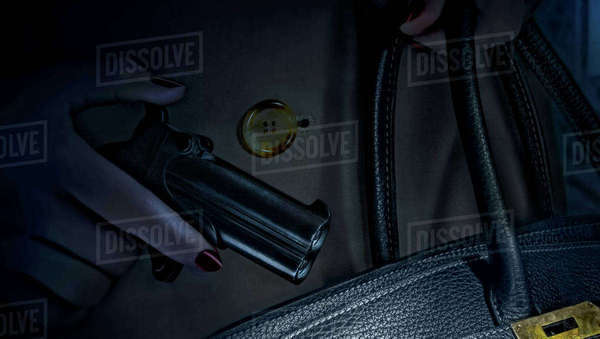 Woman putting pistol in purse - Royalty-free Stock Photo | Dissolve