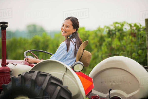 Asian woman driving tractor in field - Royalty-free Stock Photo | Dissolve