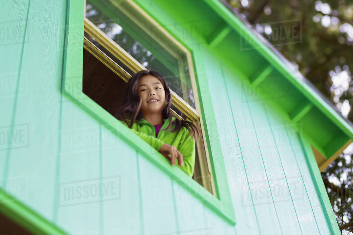 Mixed race girl leaning out window - Royalty-free Stock Photo | Dissolve