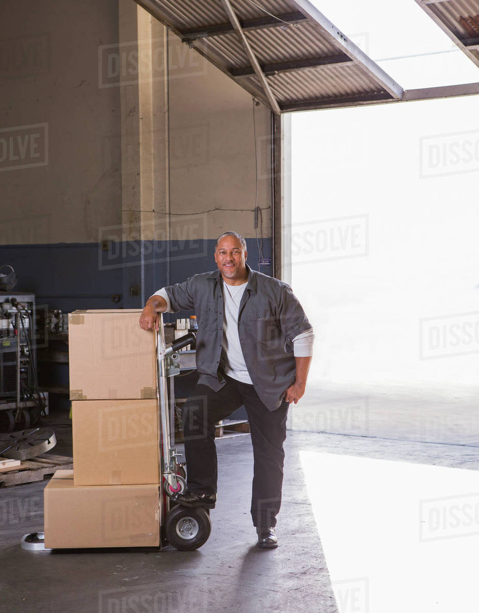 Worker with boxes on hand truck in warehouse - Stock Photo - Dissolve