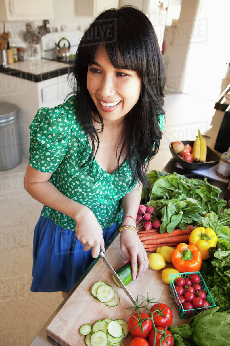 Woman chopping vegetables in kitchen - Royalty-free Stock Photo | Dissolve