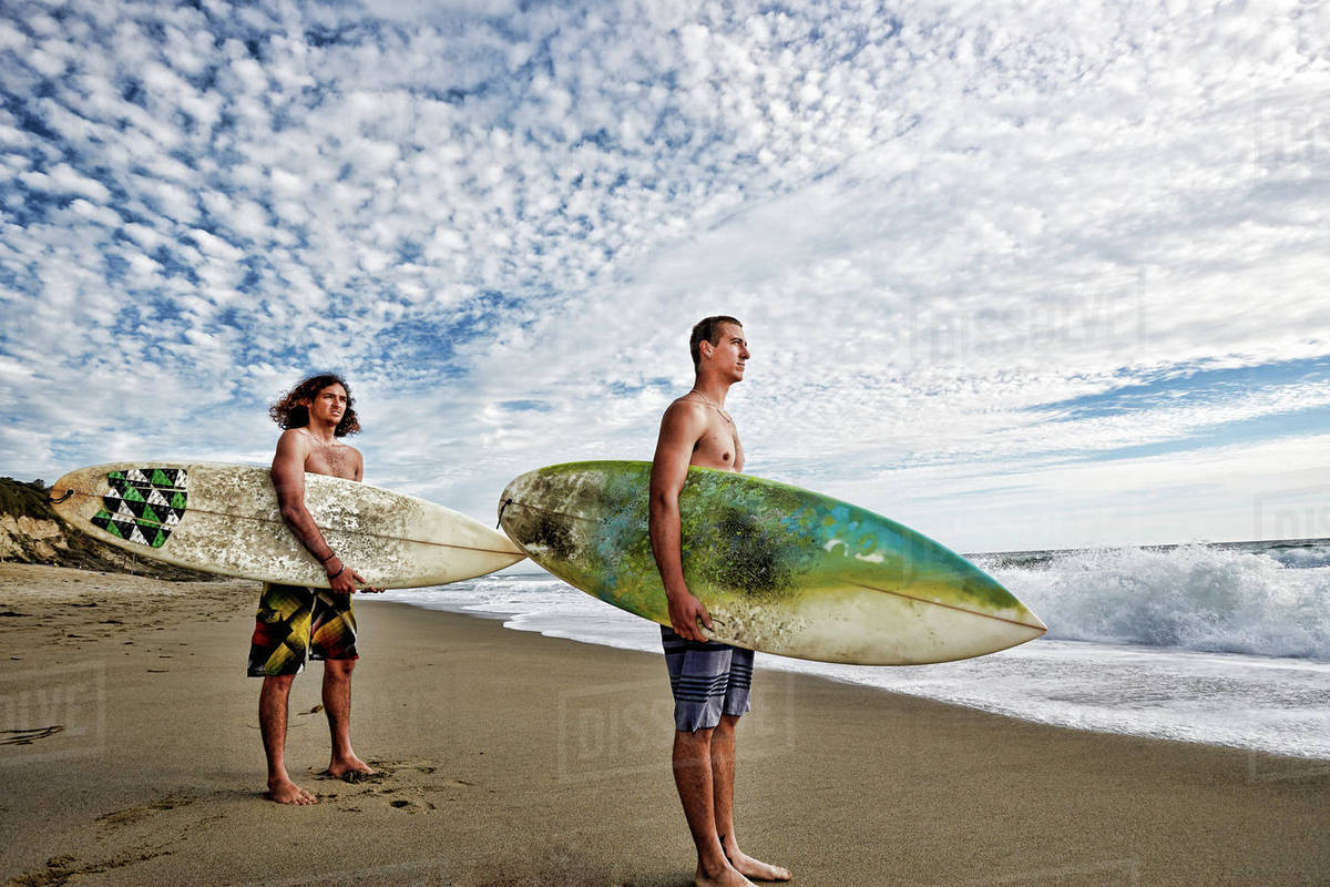 Caucasian men carrying surfboards on beach - Royalty-free Stock Photo ...