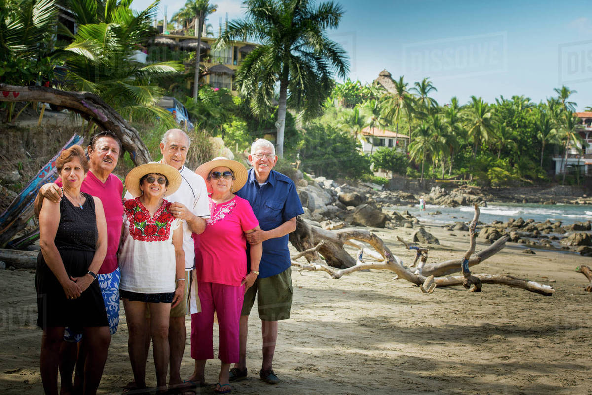 Hispanic friends smiling together on beach - Stock Photo - Dissolve
