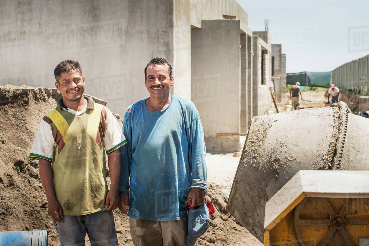 Hispanic construction workers smiling at construction site - Stock ...