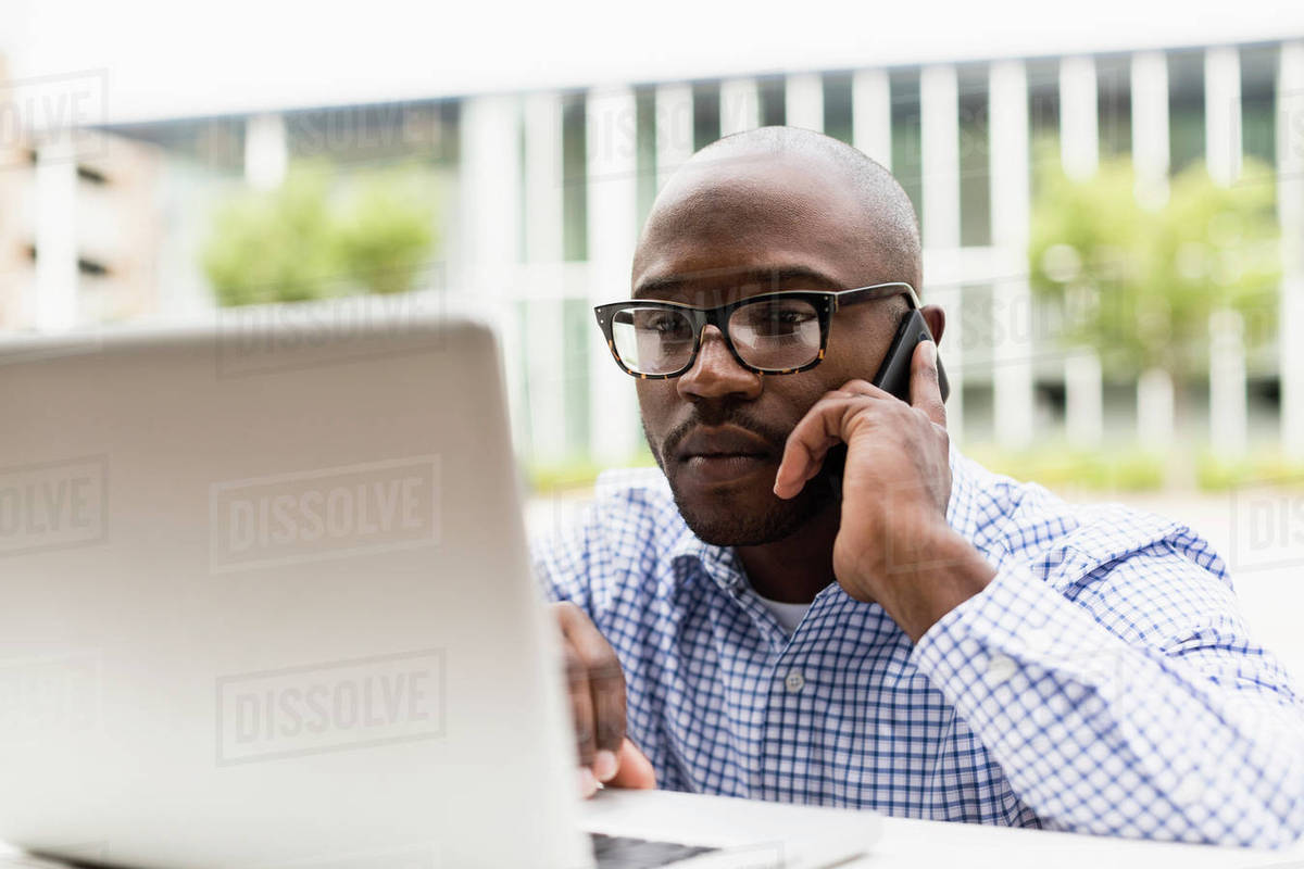Black man using cell phone and laptop outdoors - Royalty-free Stock ...