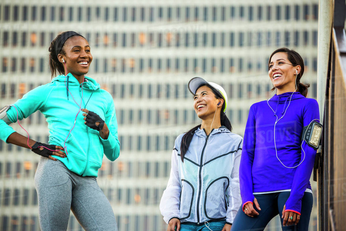 Runners laughing near highrise building - Stock Photo - Dissolve