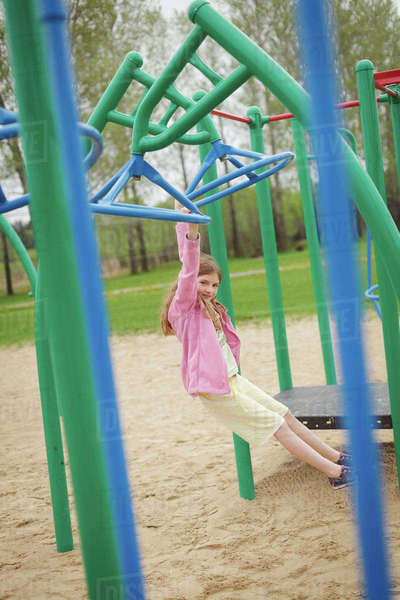 Caucasian girl hanging from structure in playground - Stock Photo ...