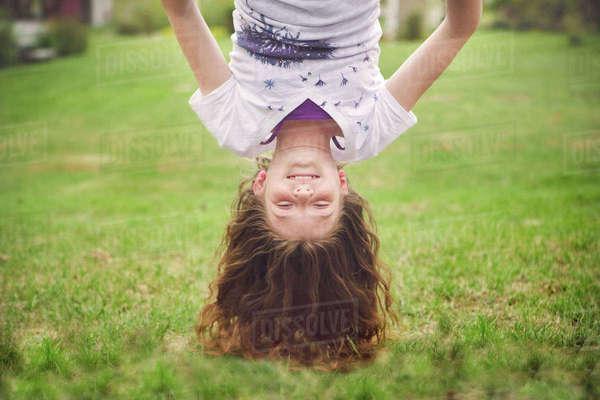 Caucasian girl hanging upside down in backyard - Stock Photo - Dissolve