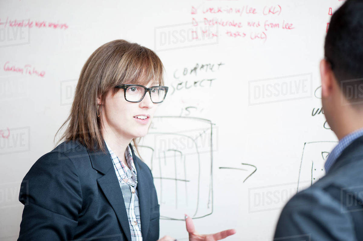 Business people writing on whiteboard in office - Stock Photo - Dissolve