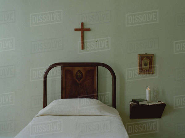 Crucifix over bed in simple bedroom - Stock Photo - Dissolve