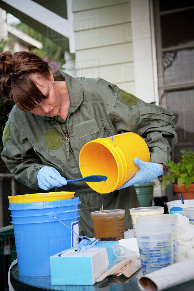 Woman pouring liquid in backyard - Stock Photo - Dissolve