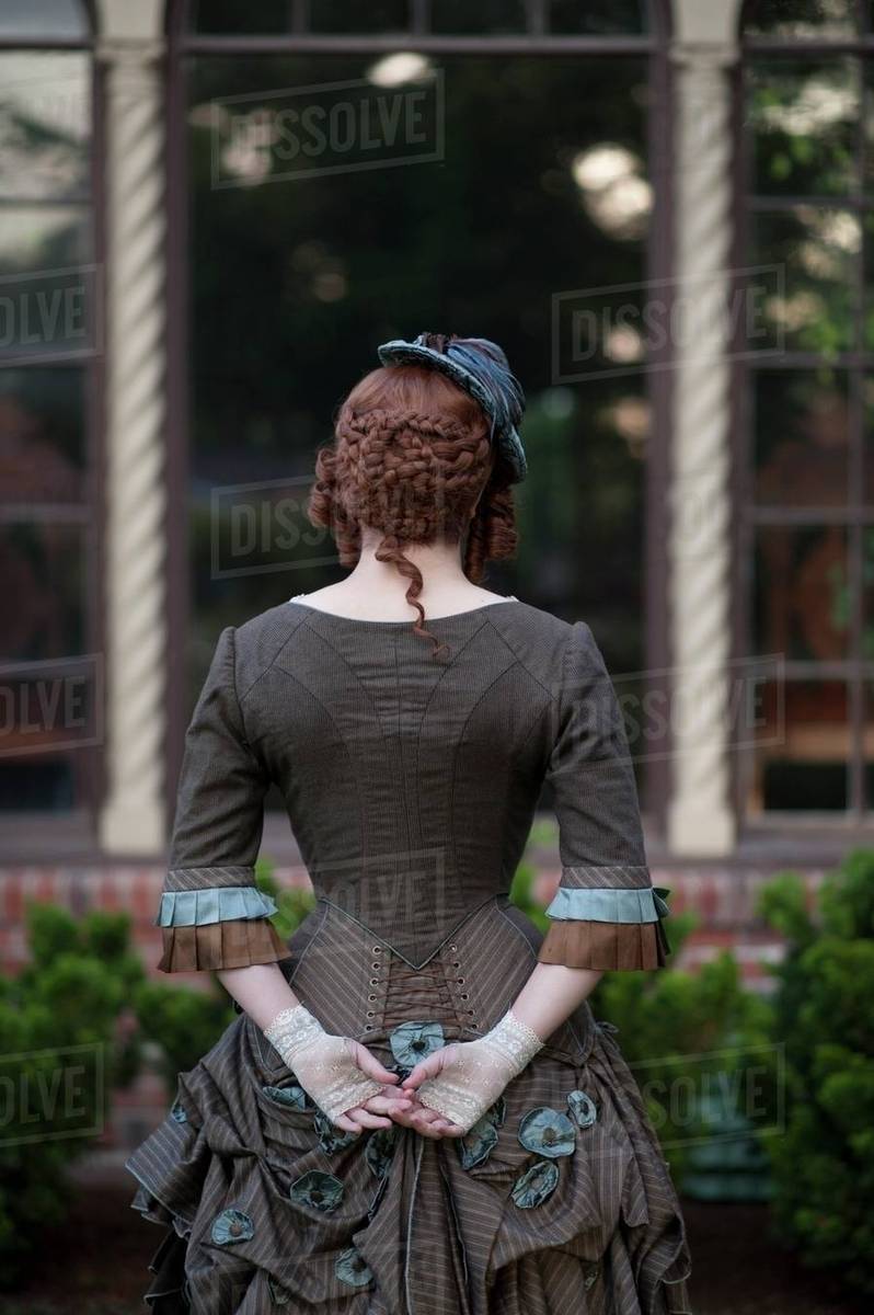 Rear view of woman wearing vintage gown and hat - Stock Photo - Dissolve