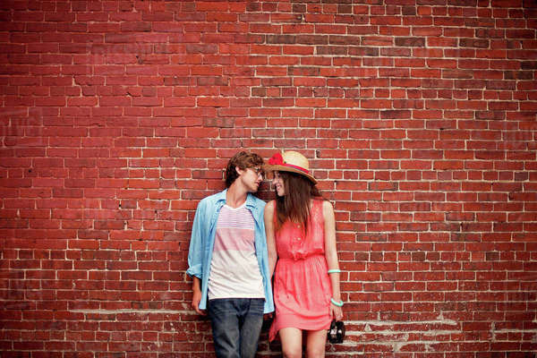 Couple leaning on brick wall - Stock Photo - Dissolve