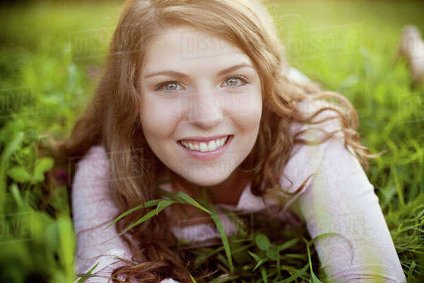 Smiling woman laying in rural field - Stock Photo - Dissolve