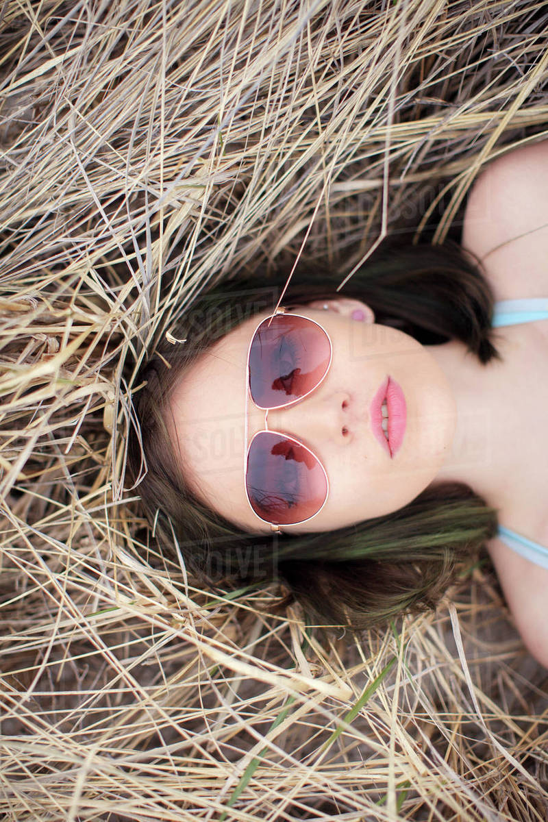 Caucasian woman laying in hay - Stock Photo - Dissolve