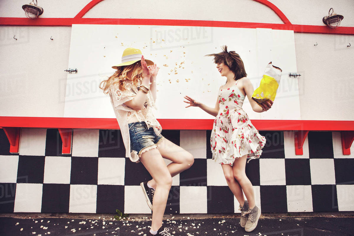Caucasian friends having popcorn fight outdoors - Stock Photo - Dissolve
