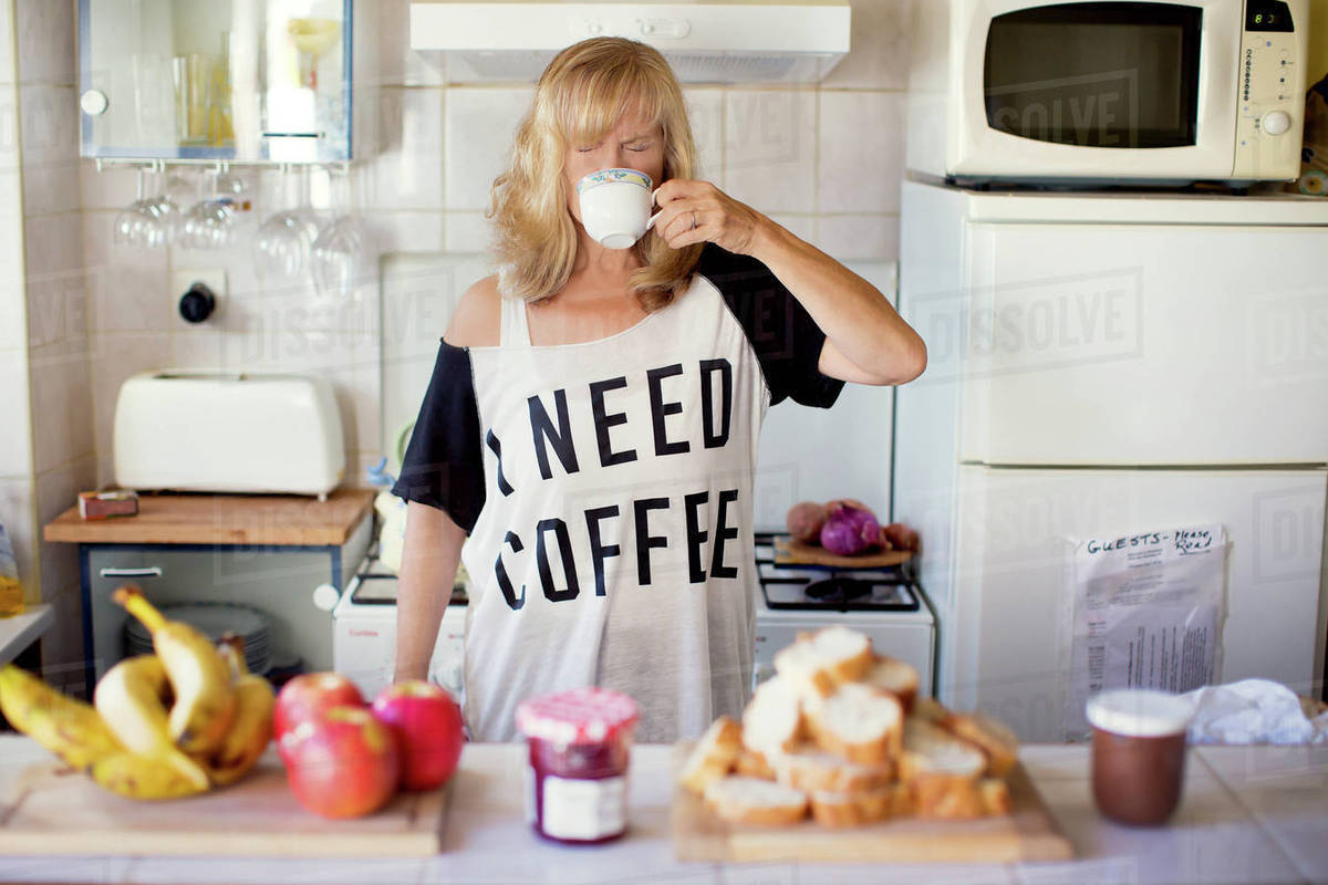 Caucasian woman drinking coffee in kitchen - Stock Photo - Dissolve