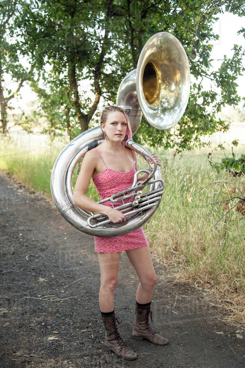 Caucasian musician carrying tuba on dirt path - Stock Photo - Dissolve