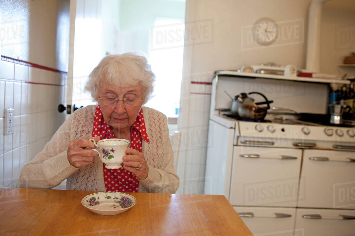 Older woman drinking tea in kitchen - Stock Photo - Dissolve
