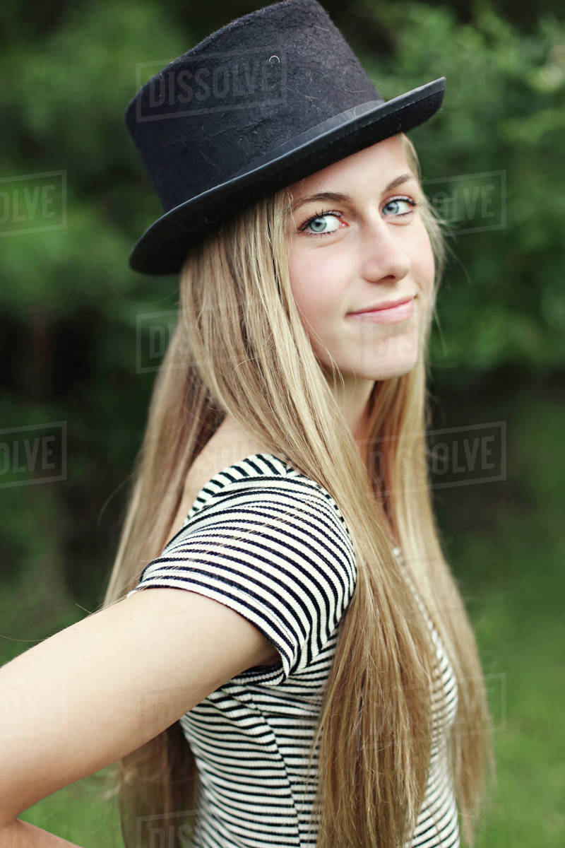 Smiling woman wearing top hat outdoors - Stock Photo - Dissolve