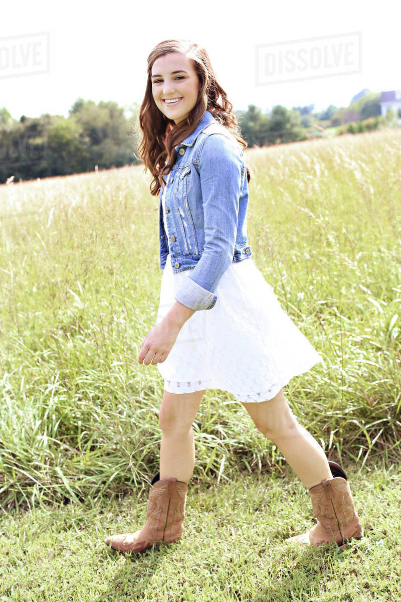 Woman walking in tall grass in field - Stock Photo - Dissolve