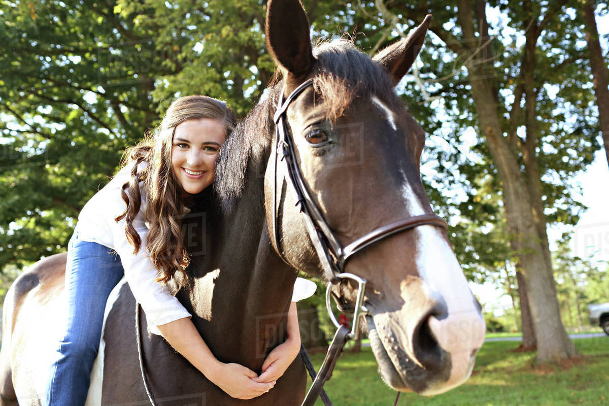 Woman hugging horse in rural field - Stock Photo - Dissolve